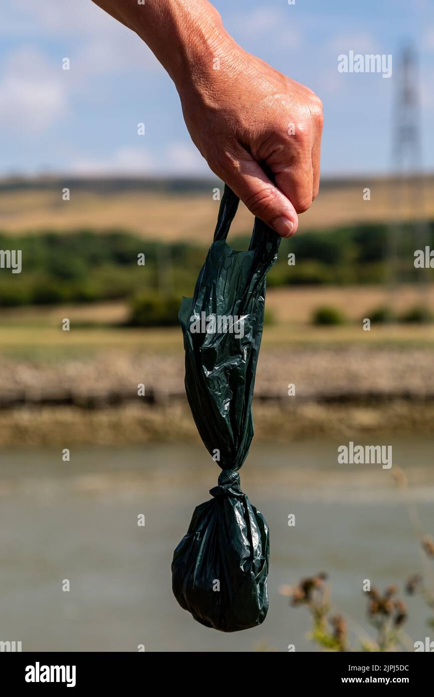 A close up of a hand holding a bag of dog poo Stock Photo - Alamy