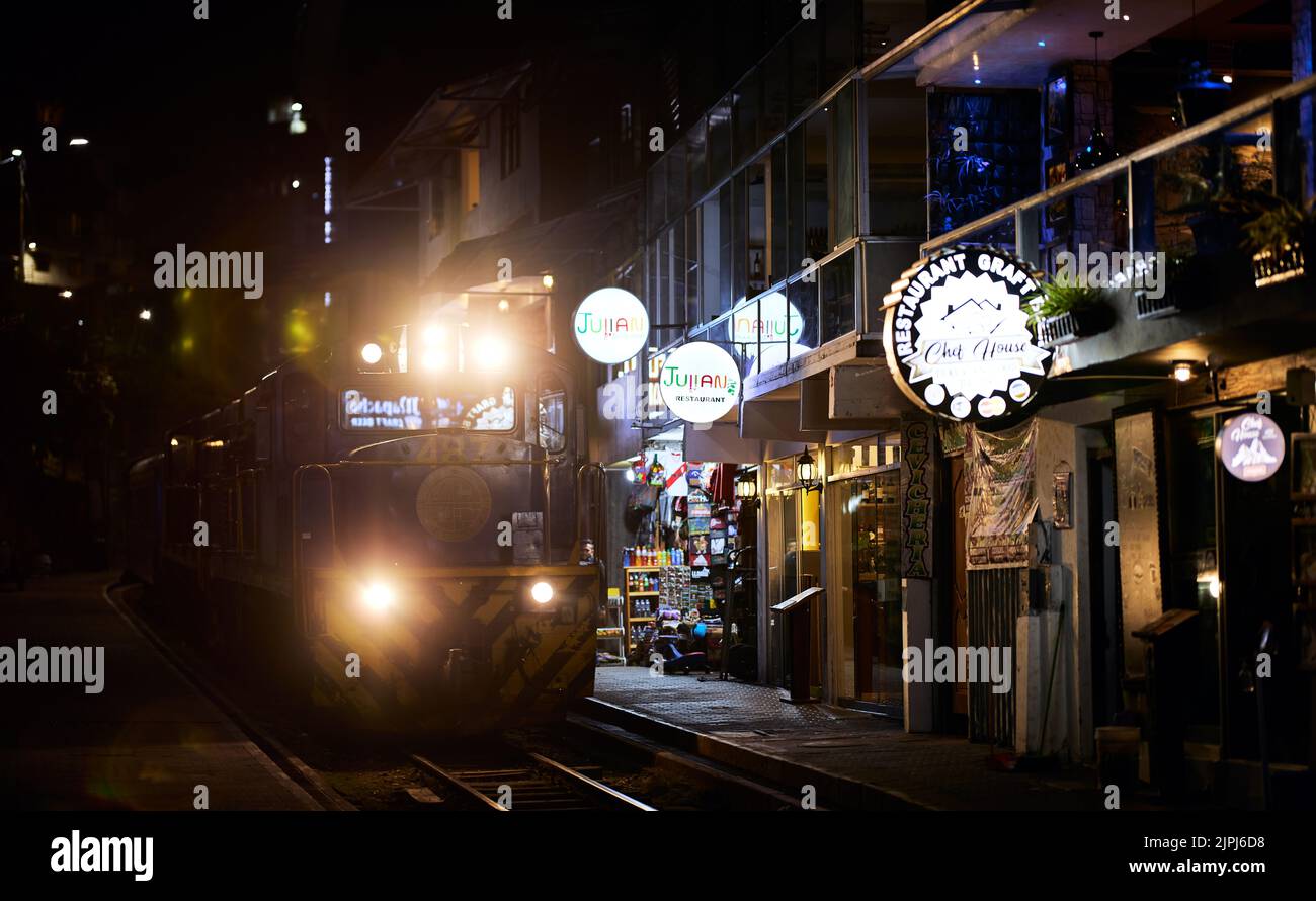 A train on a railway in a city surrounded by buildings illuminated by ...