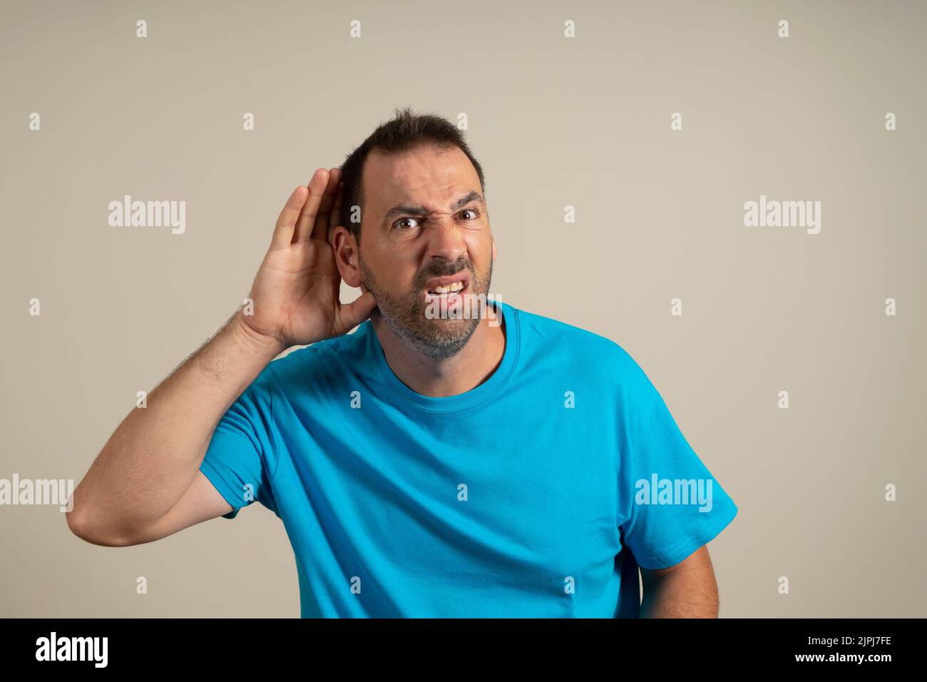 Listening man holds his hand near his ear on a beige background ...