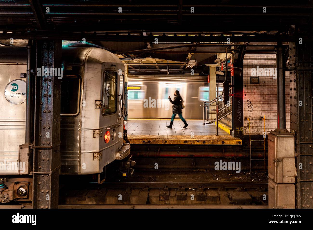 A person walking on a station near a passing train in Manhattan, NYC ...