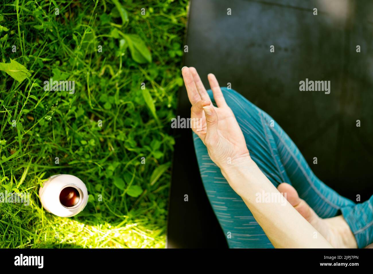 A young girl meditates in the park. The hand in gyan mudra, green grass ...