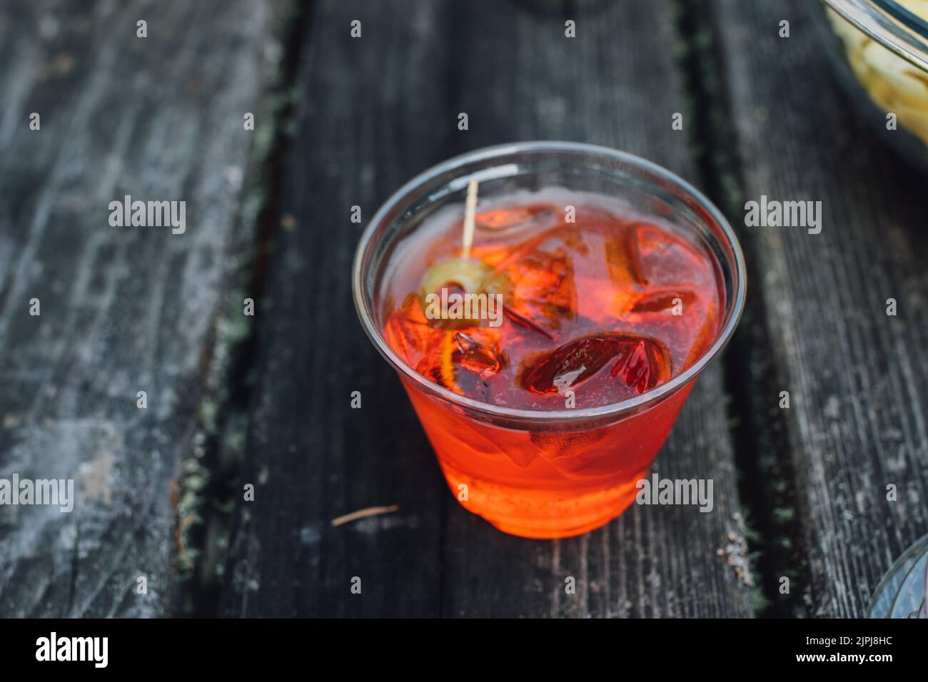 aperol spritz cocktail with green olive garnish on picnic table Stock ...
