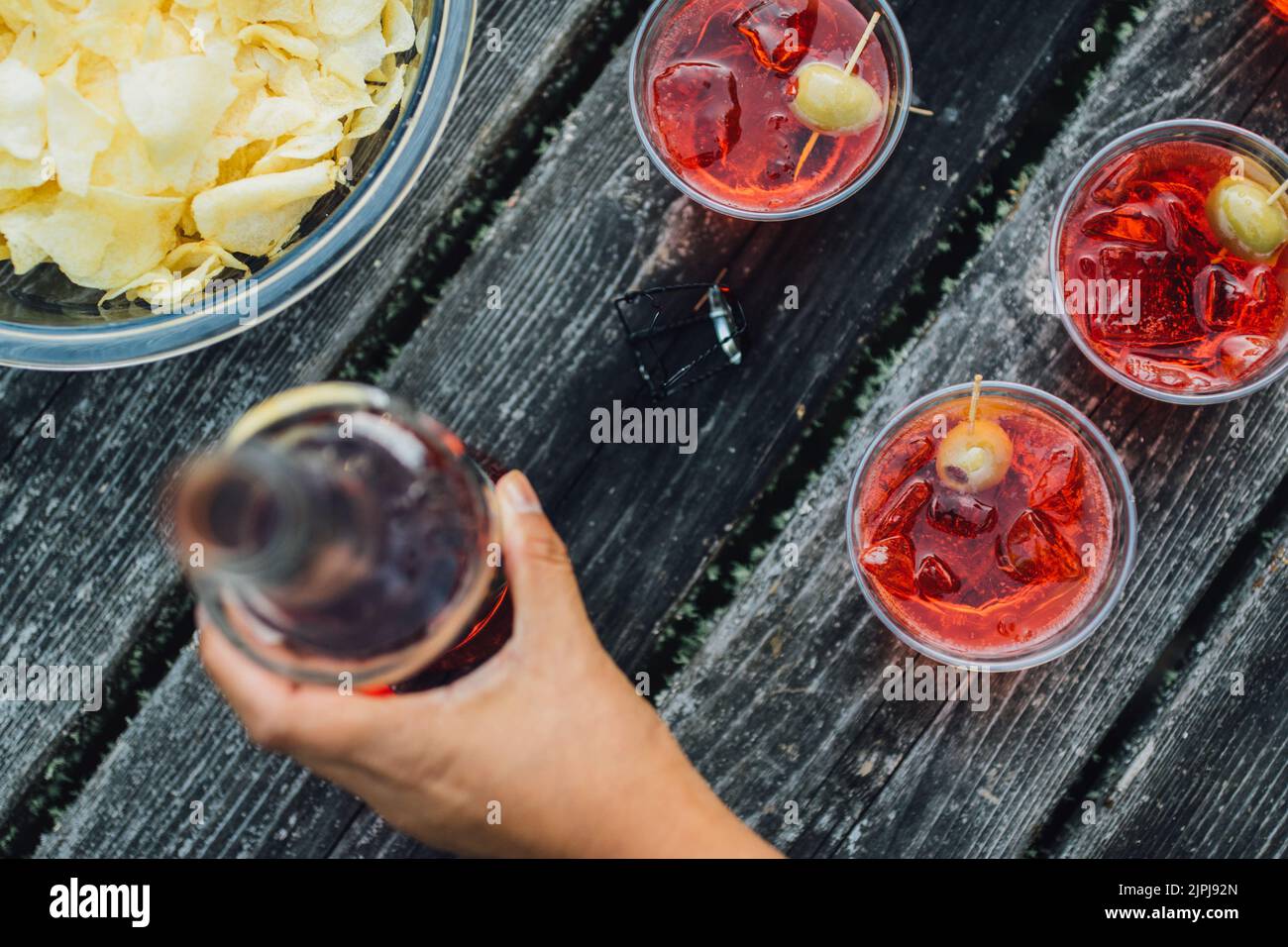 Making aperol spritz cocktails outdoors on picnic table with bowl of ...