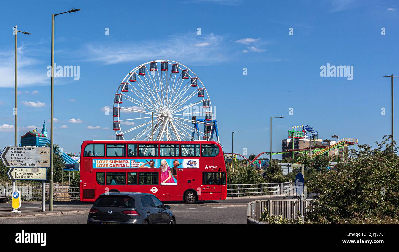 A double decker TFL bus passing by a fun fair ferris wheel, Brent Cross ...