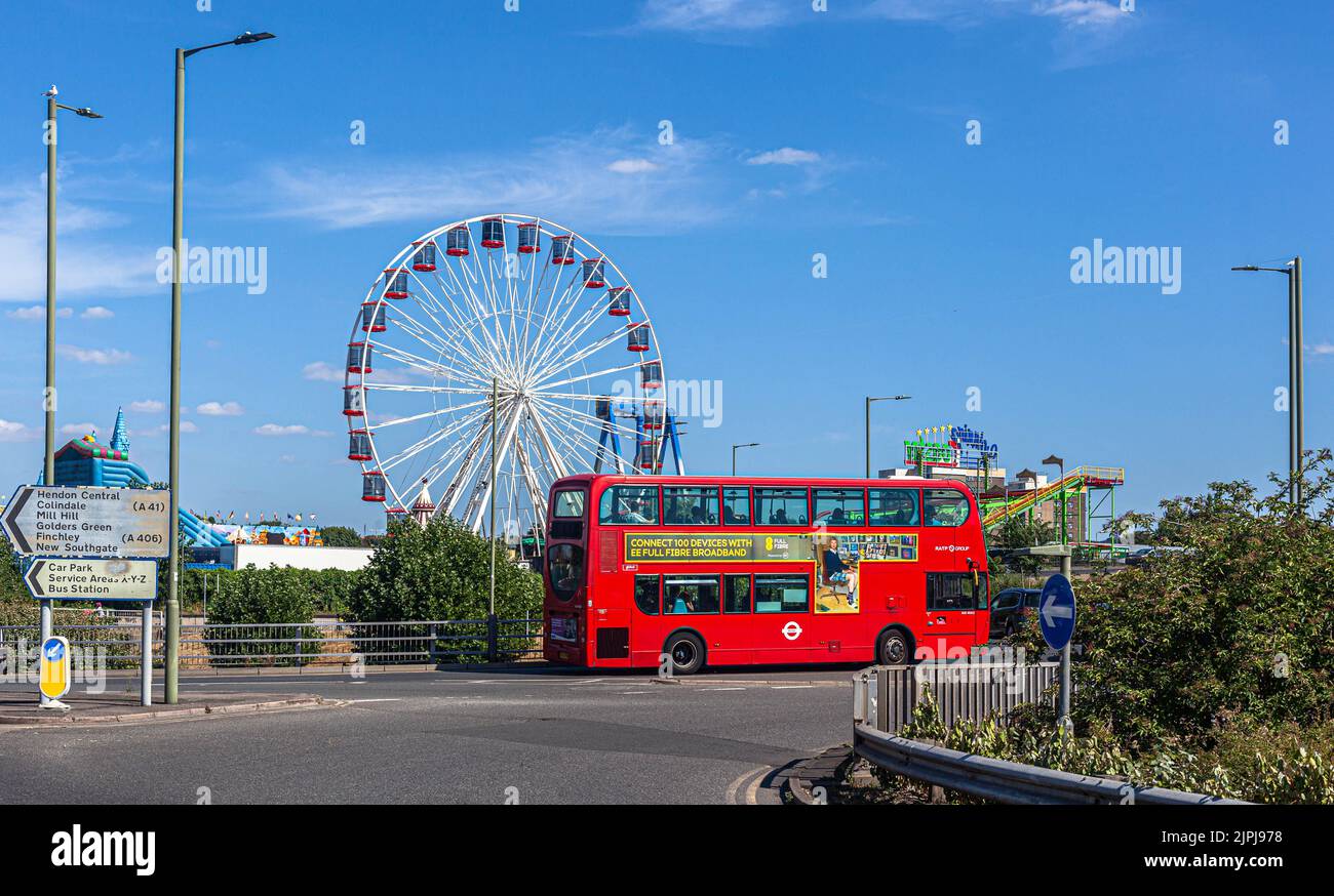 A double decker TFL bus passing by a fun fair ferris wheel, Brent Cross ...