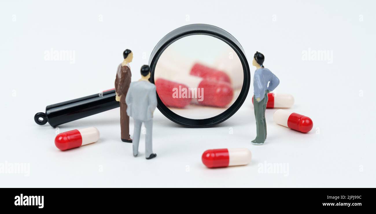 Three miniature figures of people look through a magnifying glass at ...