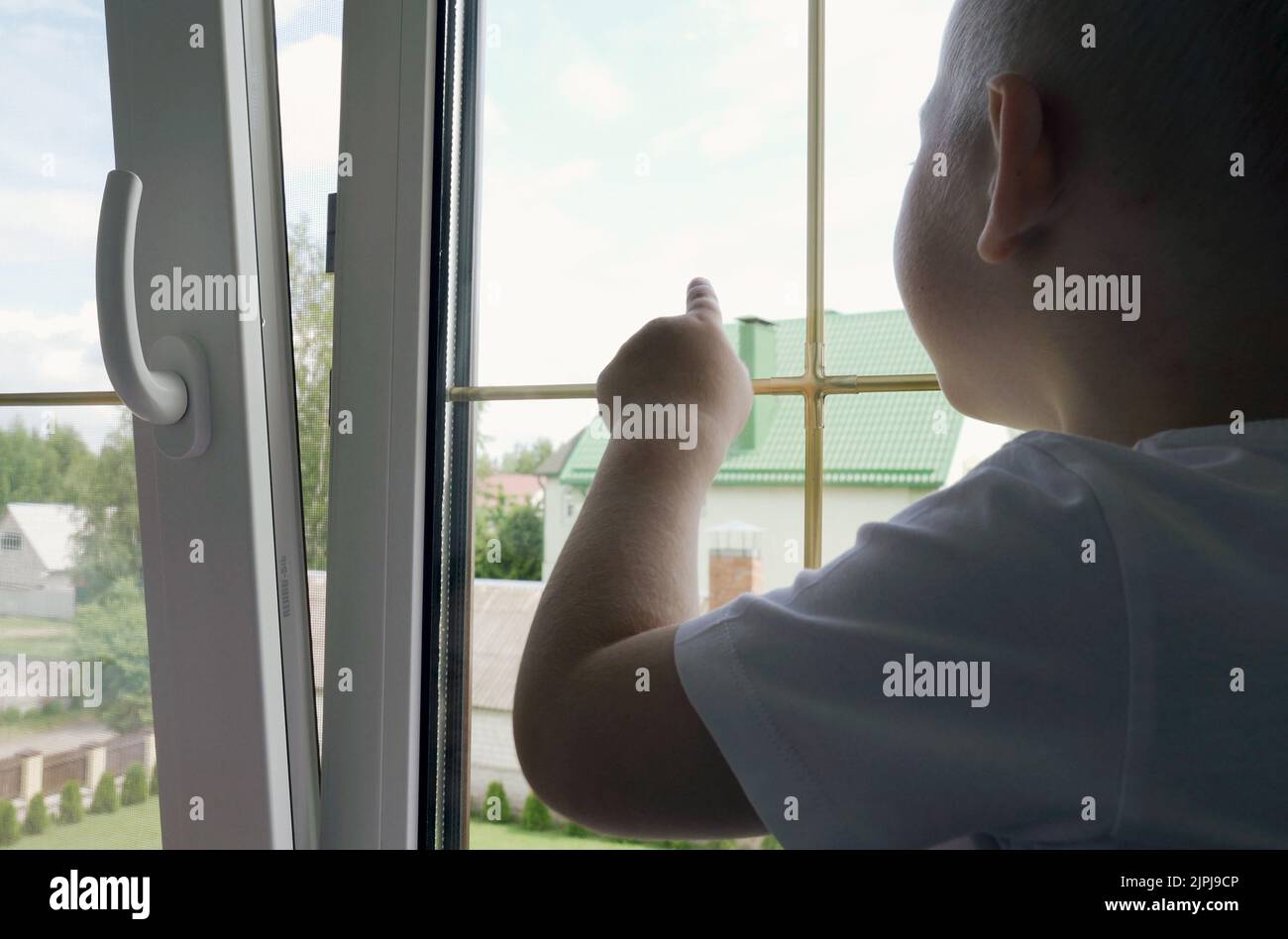 A little boy sits and looks out the window, points his finger. Close-up ...