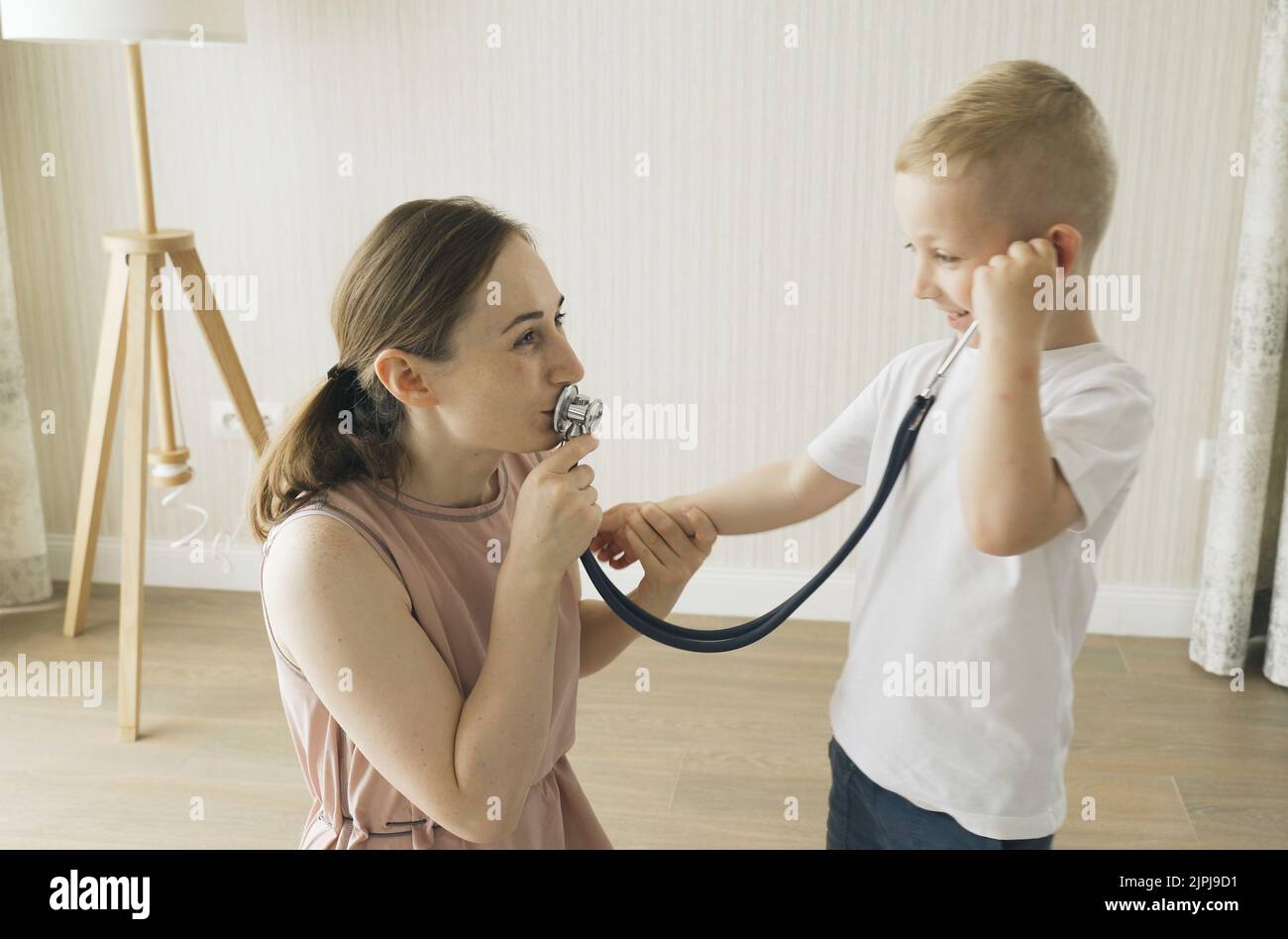 The boy listens through a stethoscope to what his mother is telling him ...