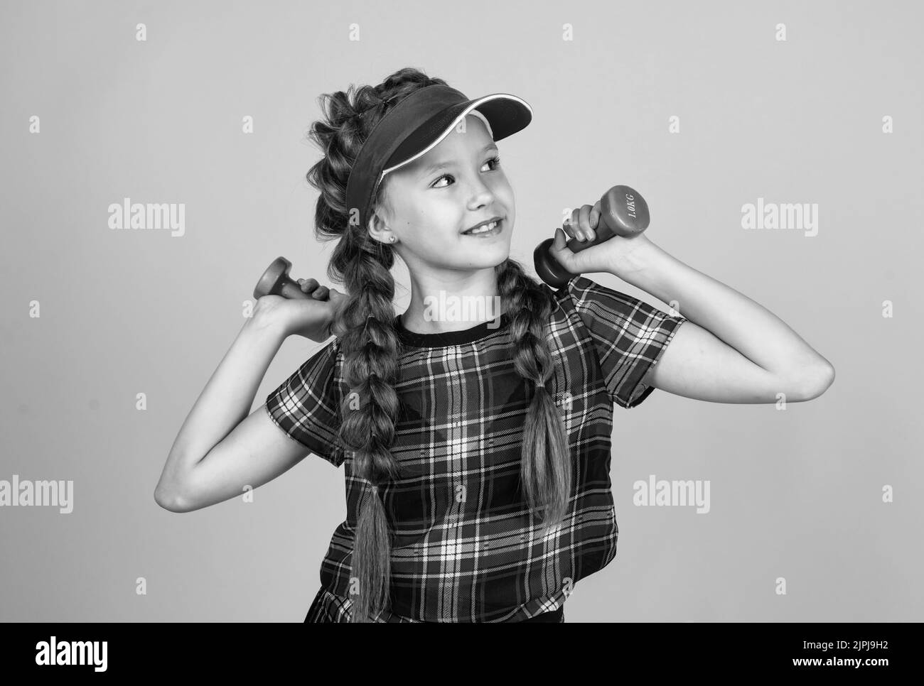 teen child in fitness cap holding barber or dumbbell sport tool ...