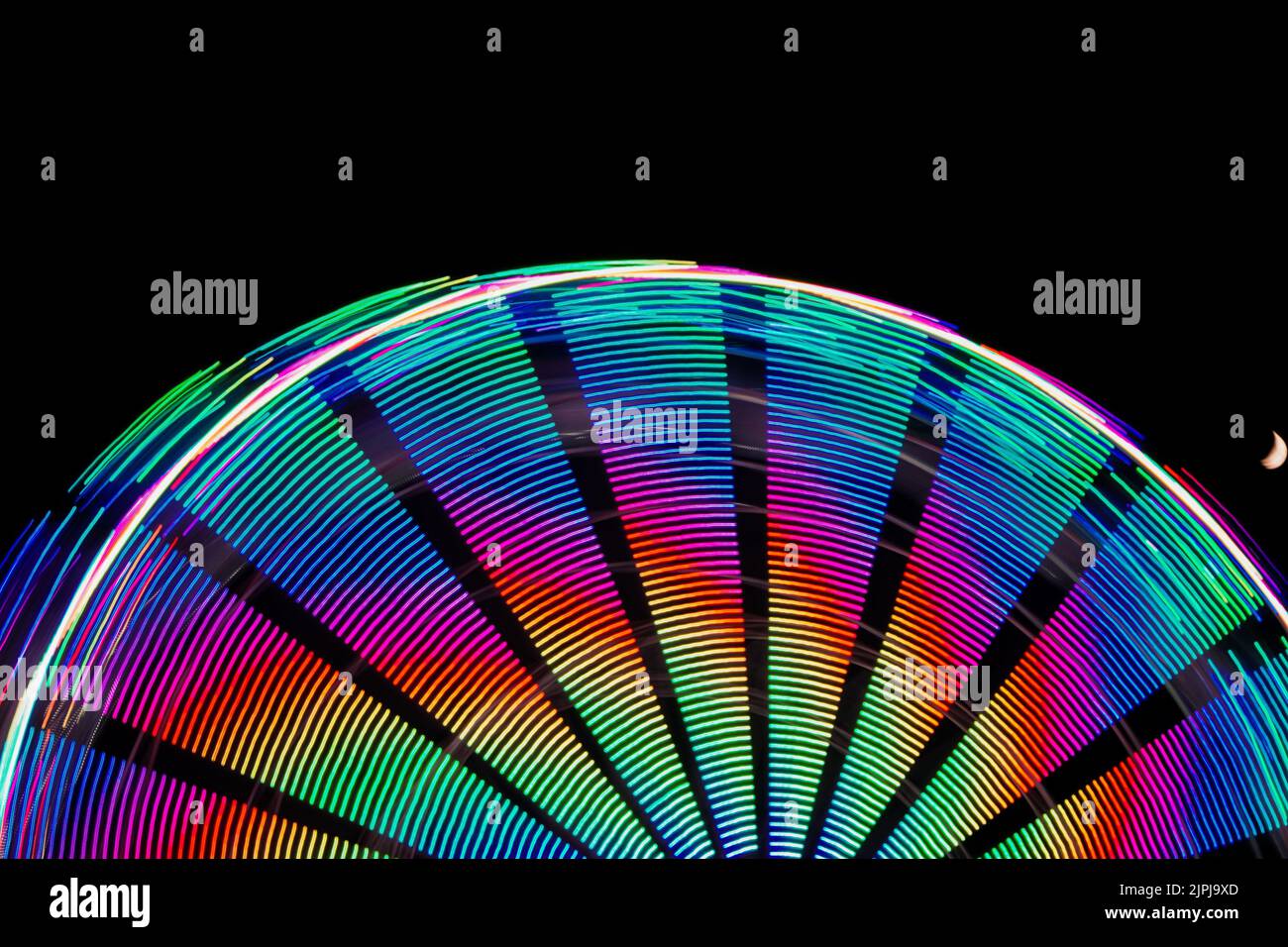 A moving Ferris Wheel in rainbow colors against dark sky Stock Photo ...