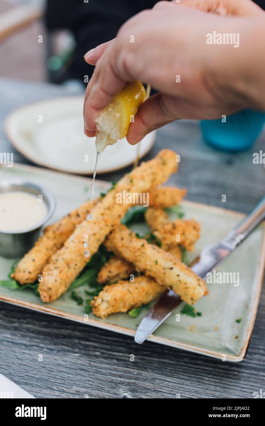 hands squeezing lemon juice onto calamari strips Stock Photo - Alamy