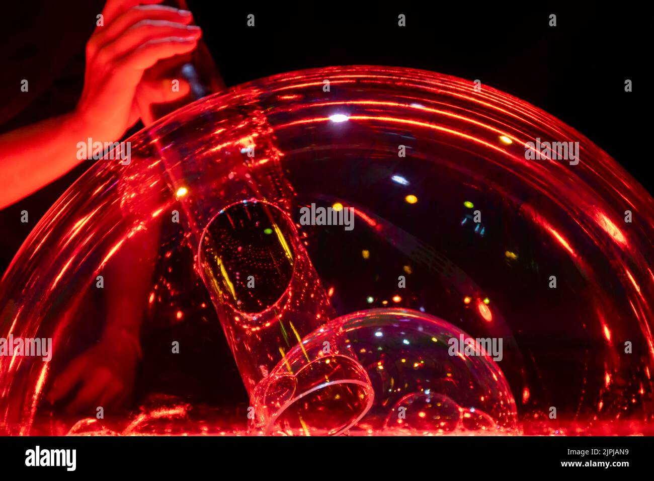 blowing double soap bubble made with a tube and illuminated in red ...