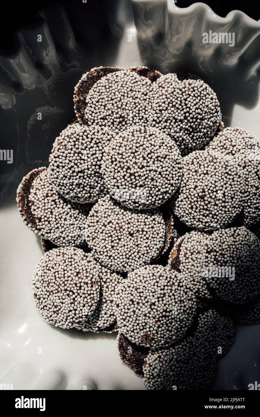 dark chocolate nonpareils with white sprinkles in white milk glass ...