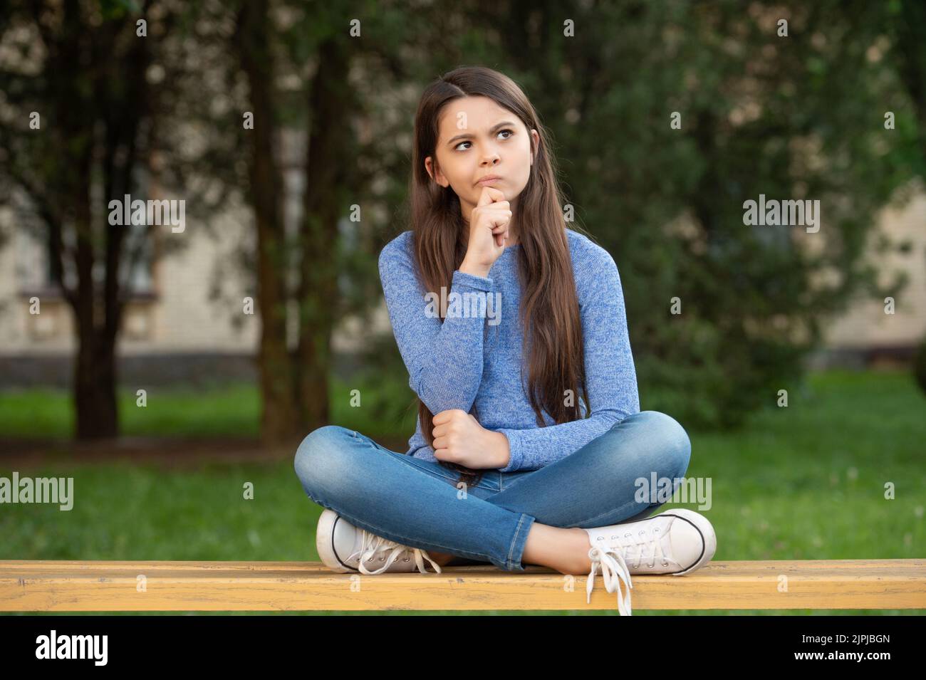Thinking girl teenager thinking while sitting legs crossed on bench ...