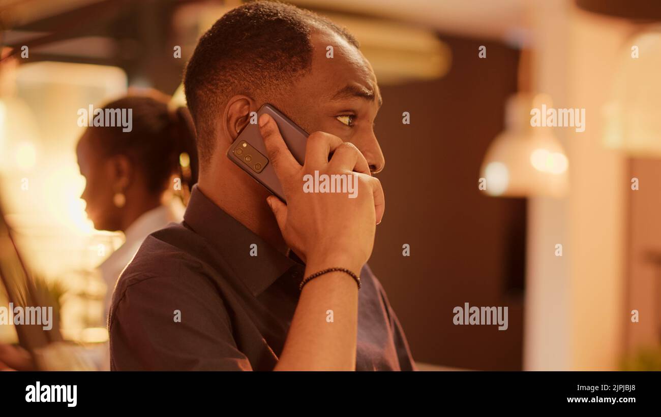 African american man talking on mobile phone call at office desk, using ...