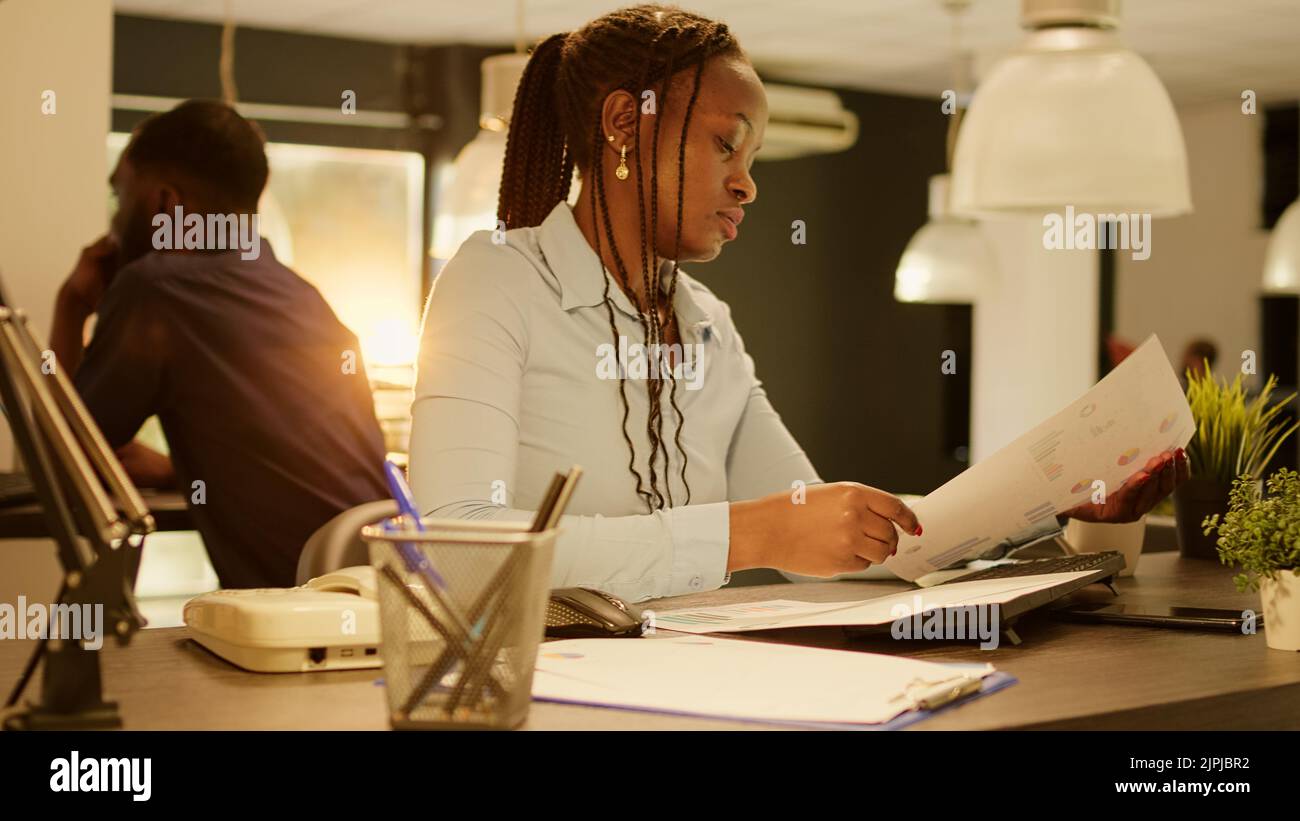 African american woman analyzing business paperwork with charts and ...