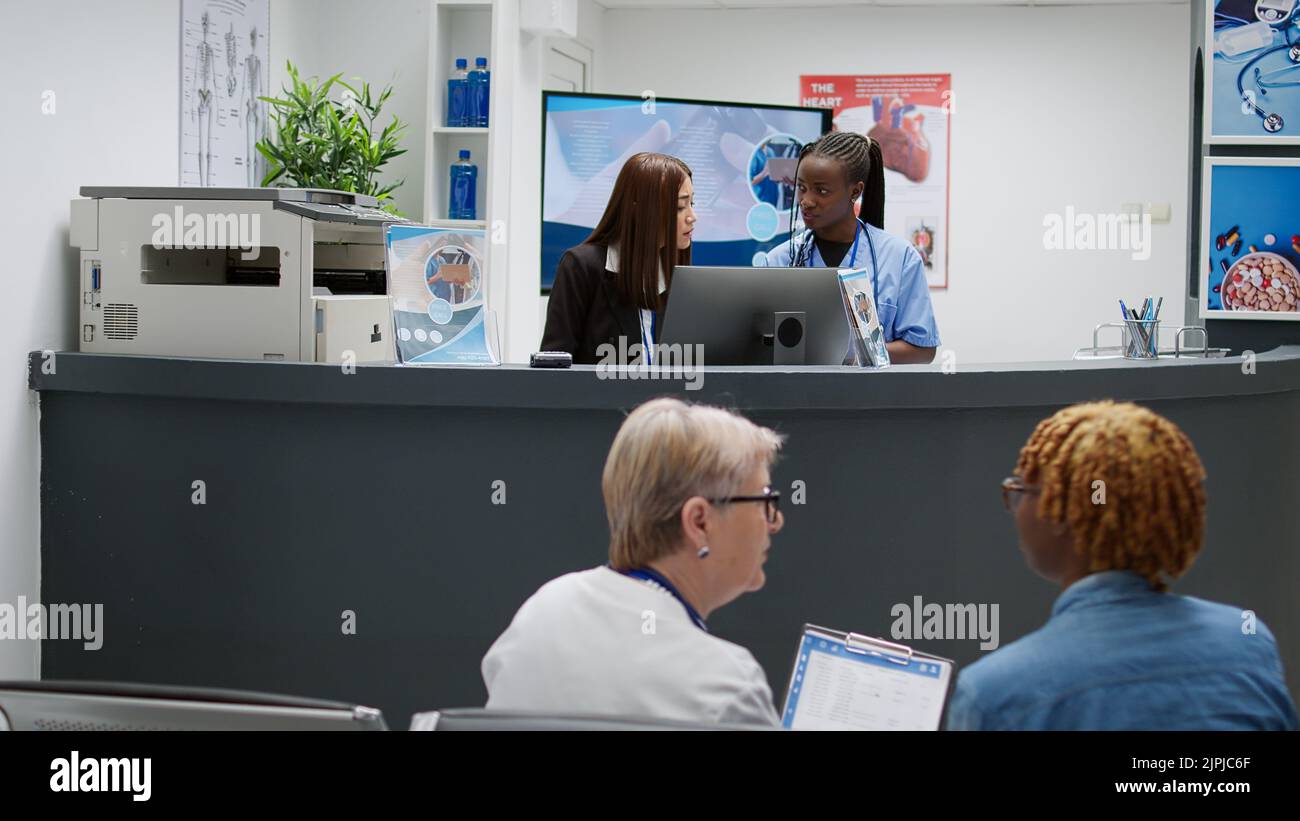 Medical assistant and receptionist working at facility reception ...