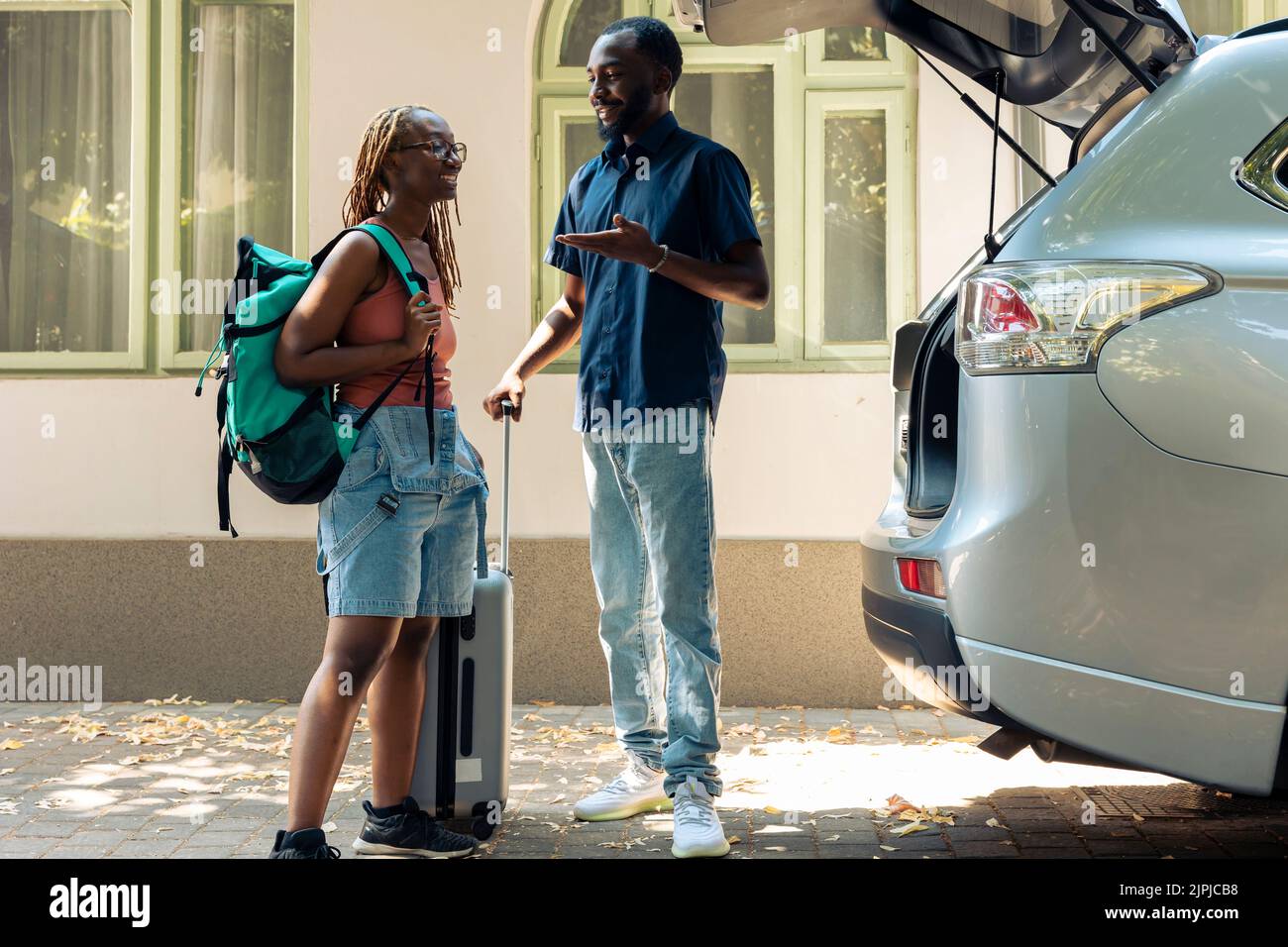 African american couple travelling by car, putting luggage and baggage ...