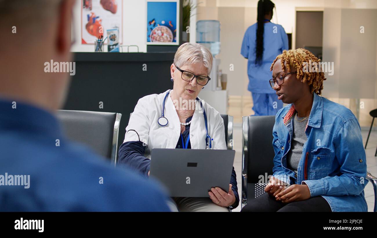 Senior medic showing diagnosis on laptop to sick patient, explaining ...