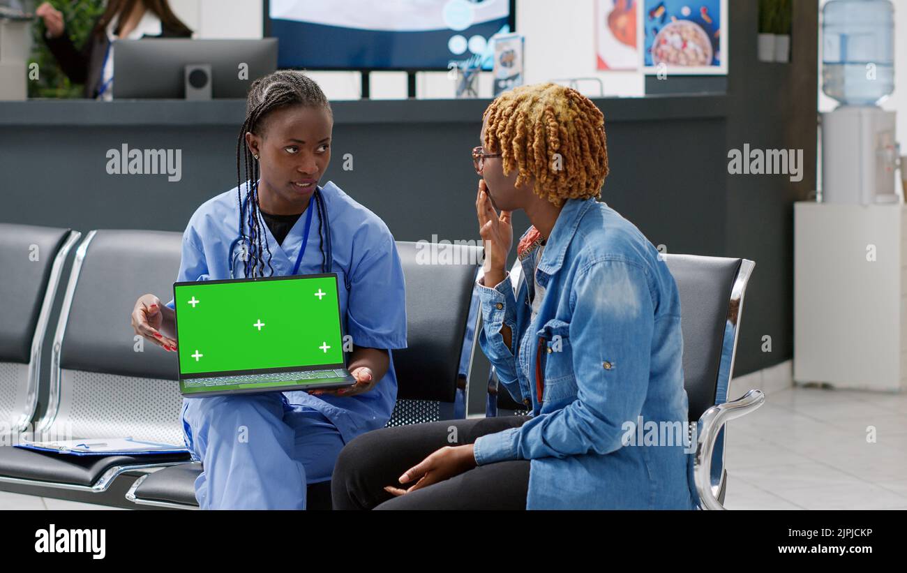 Nurse and patient looking at laptop with greenscreen display ...