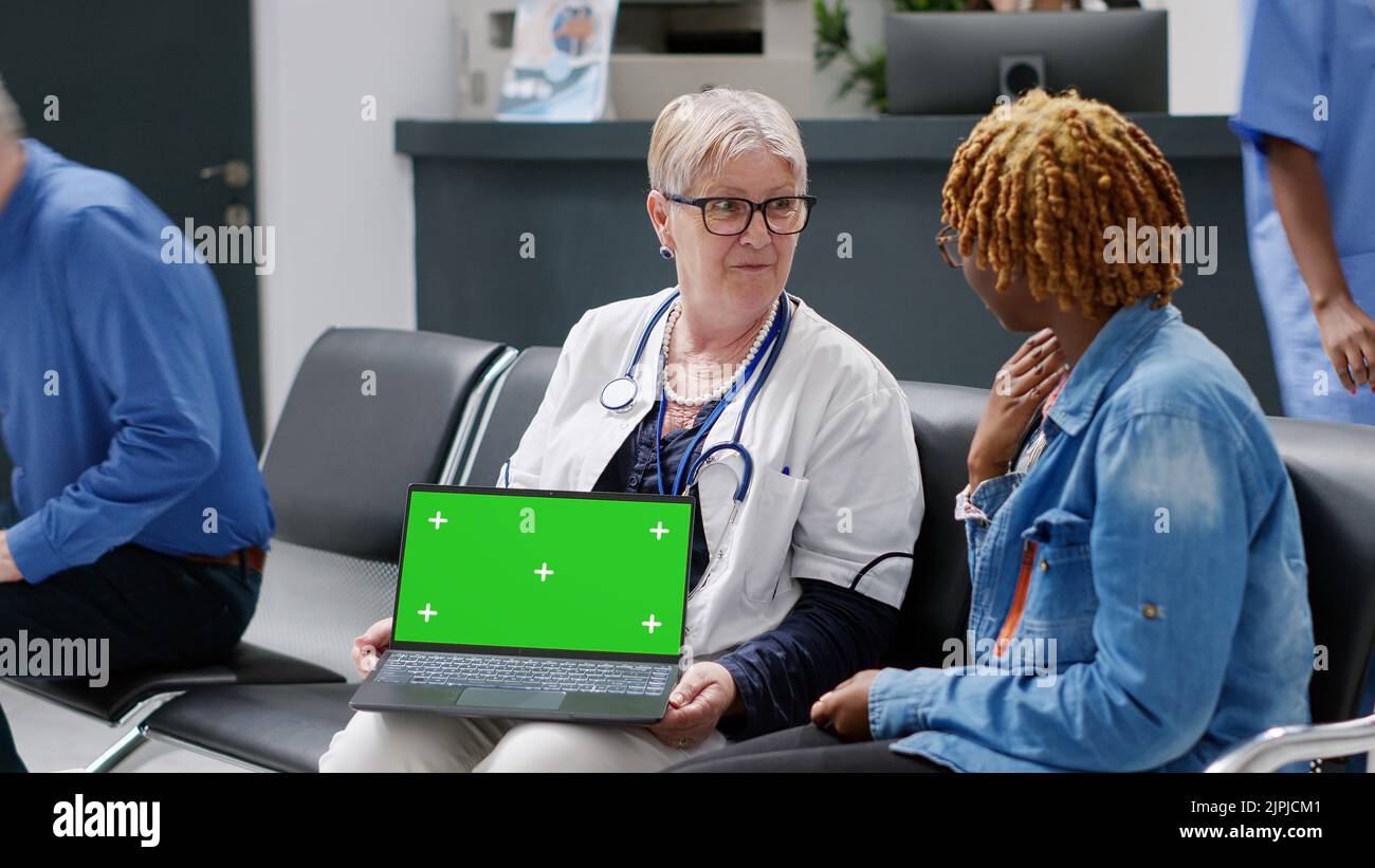 Patient and senior medic looking at laptop with greenscreen at checkup ...