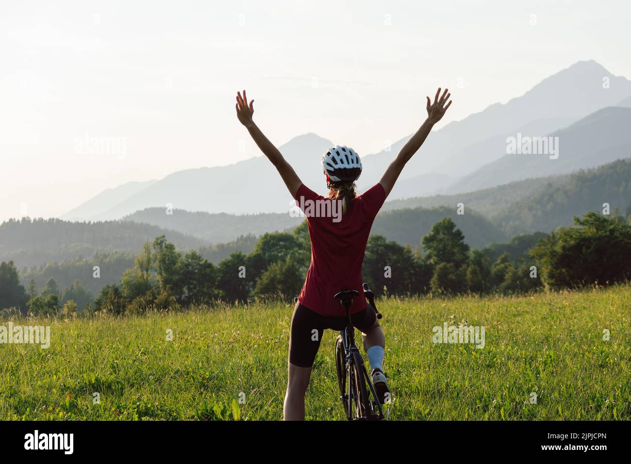 Happy female road racing cyclist in joy, with arms raised above her ...