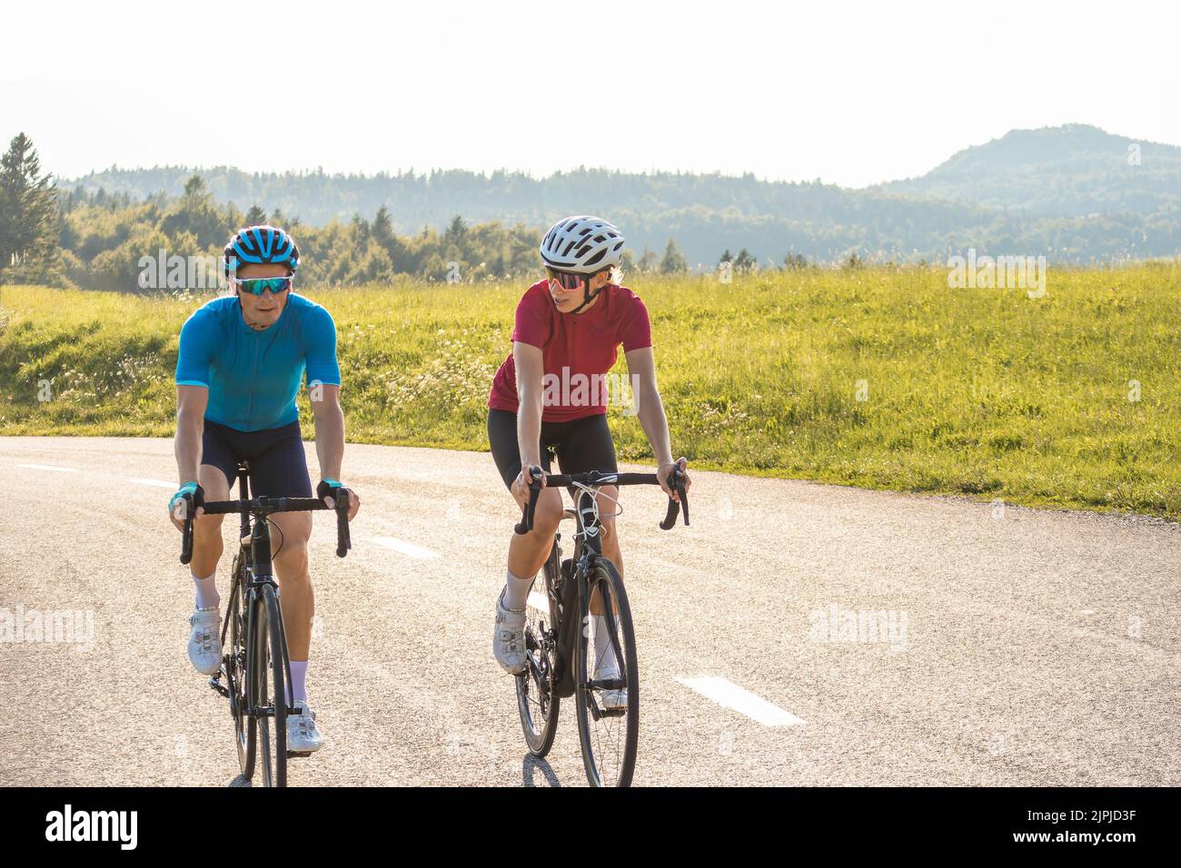 Front view of two people, a male, and female racing cyclists ride on a ...