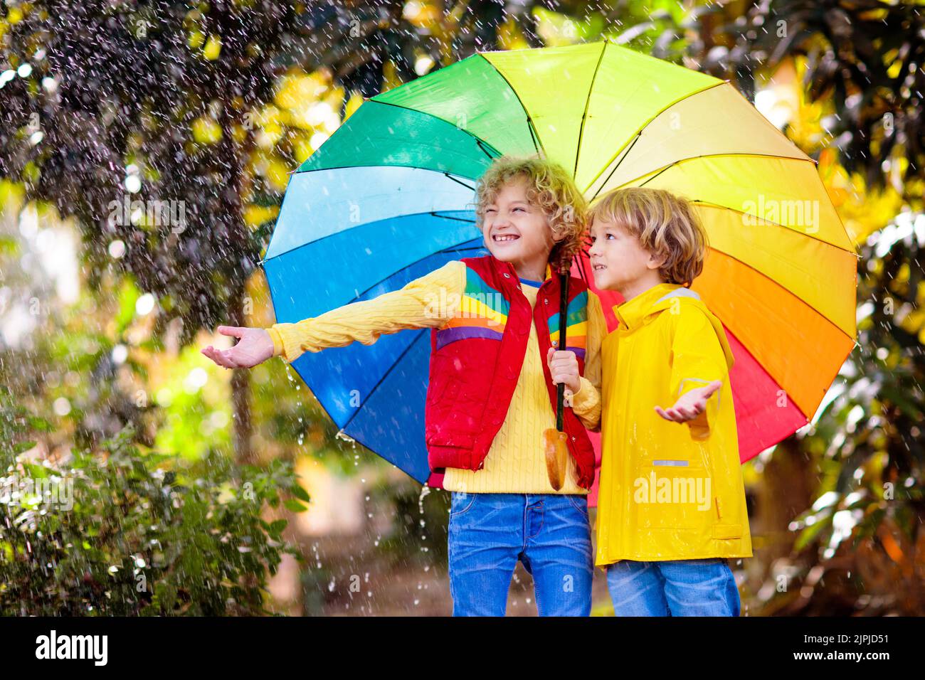 Child playing in autumn rain. Kid with umbrella. Little boy running in ...