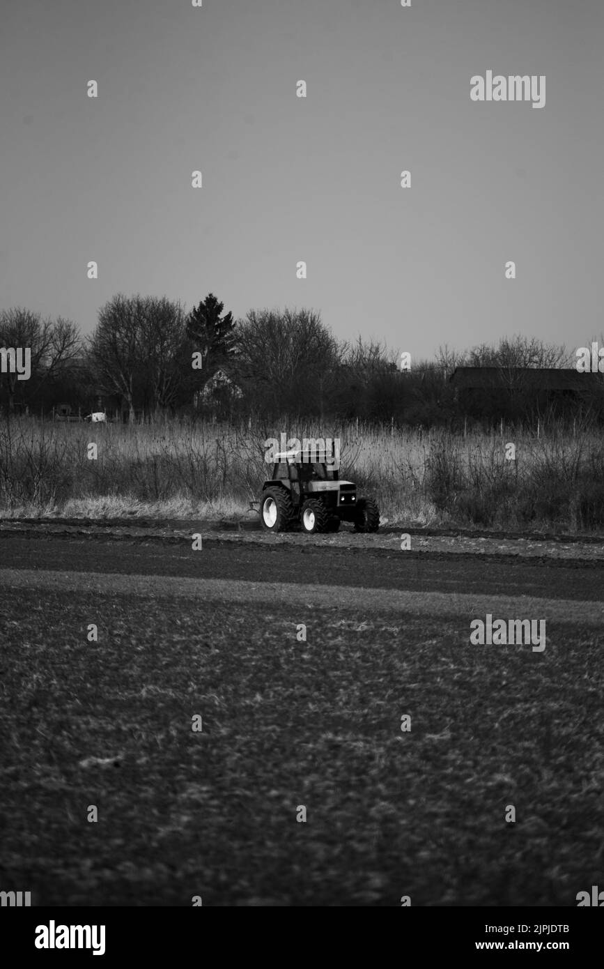 A vertical grayscale of a tractor in an agricultural field Stock Photo ...