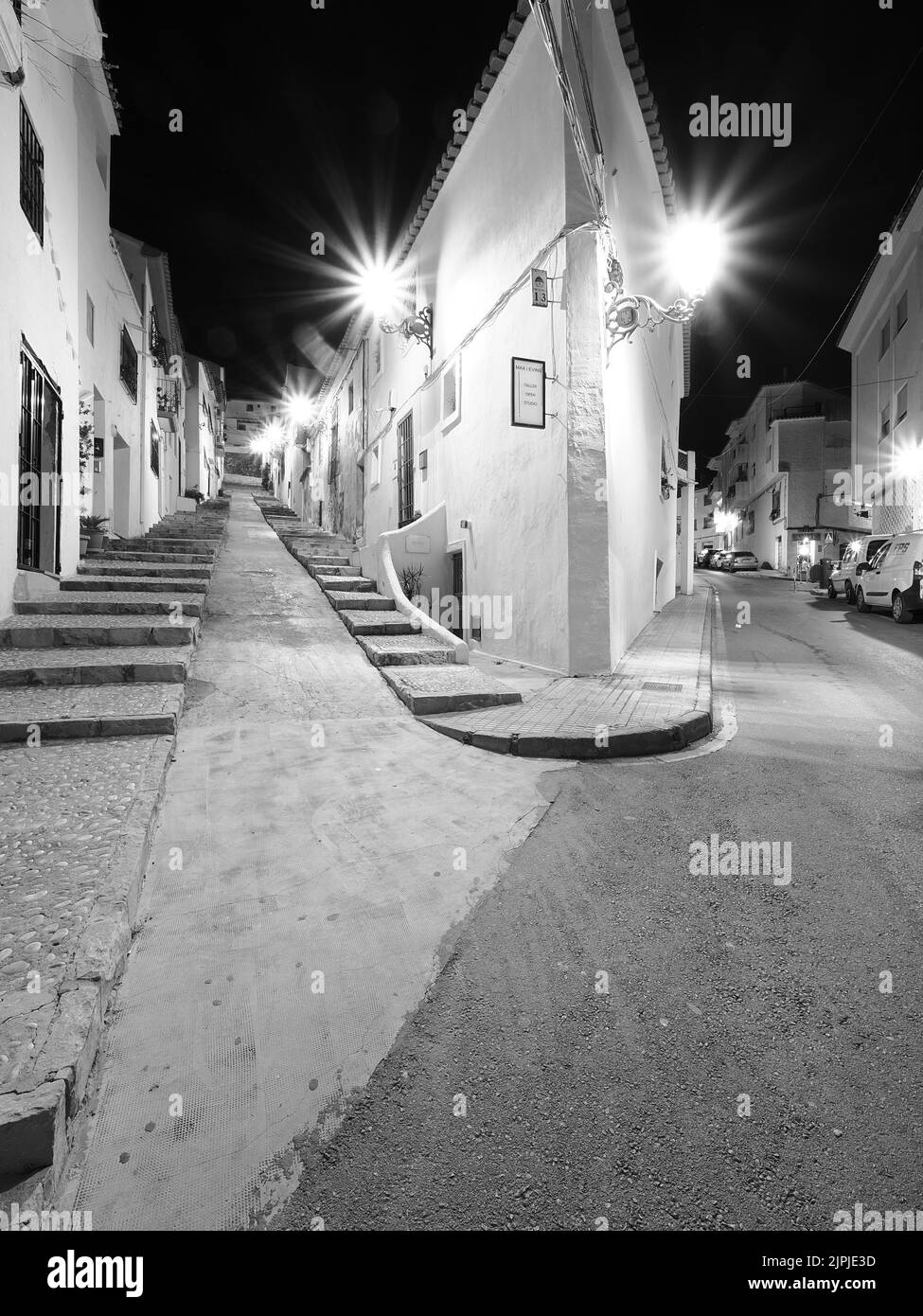 A grayscale of a street with residential buildings and illuminated ...