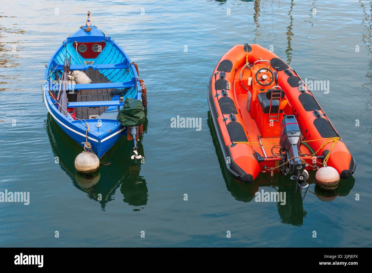 Blue double-ender boat and orange rigid-bottom inflatable boat Stock ...