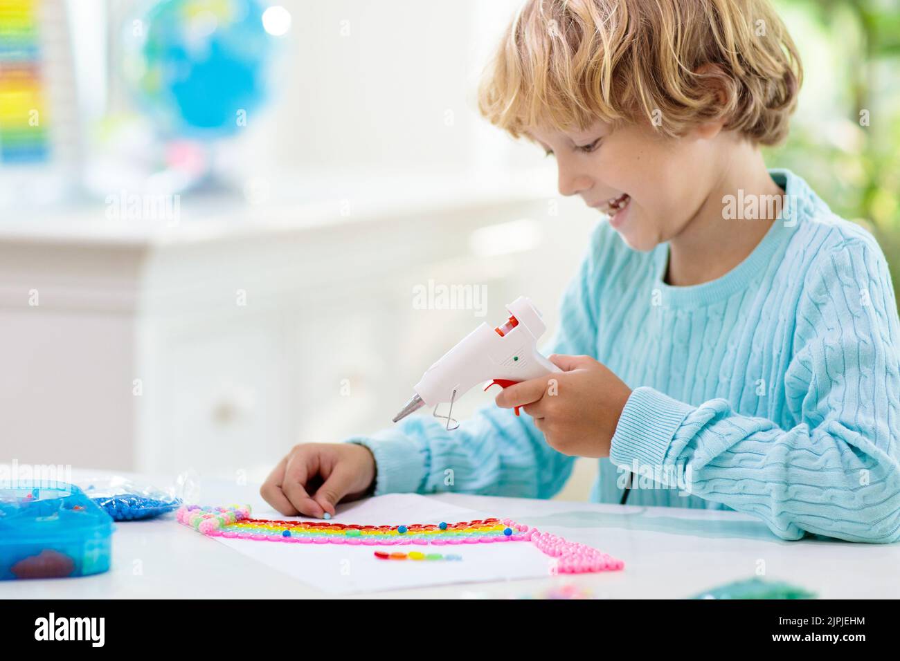 Crafts for kids. Child with hot glue gun. Creative little boy sticking ...