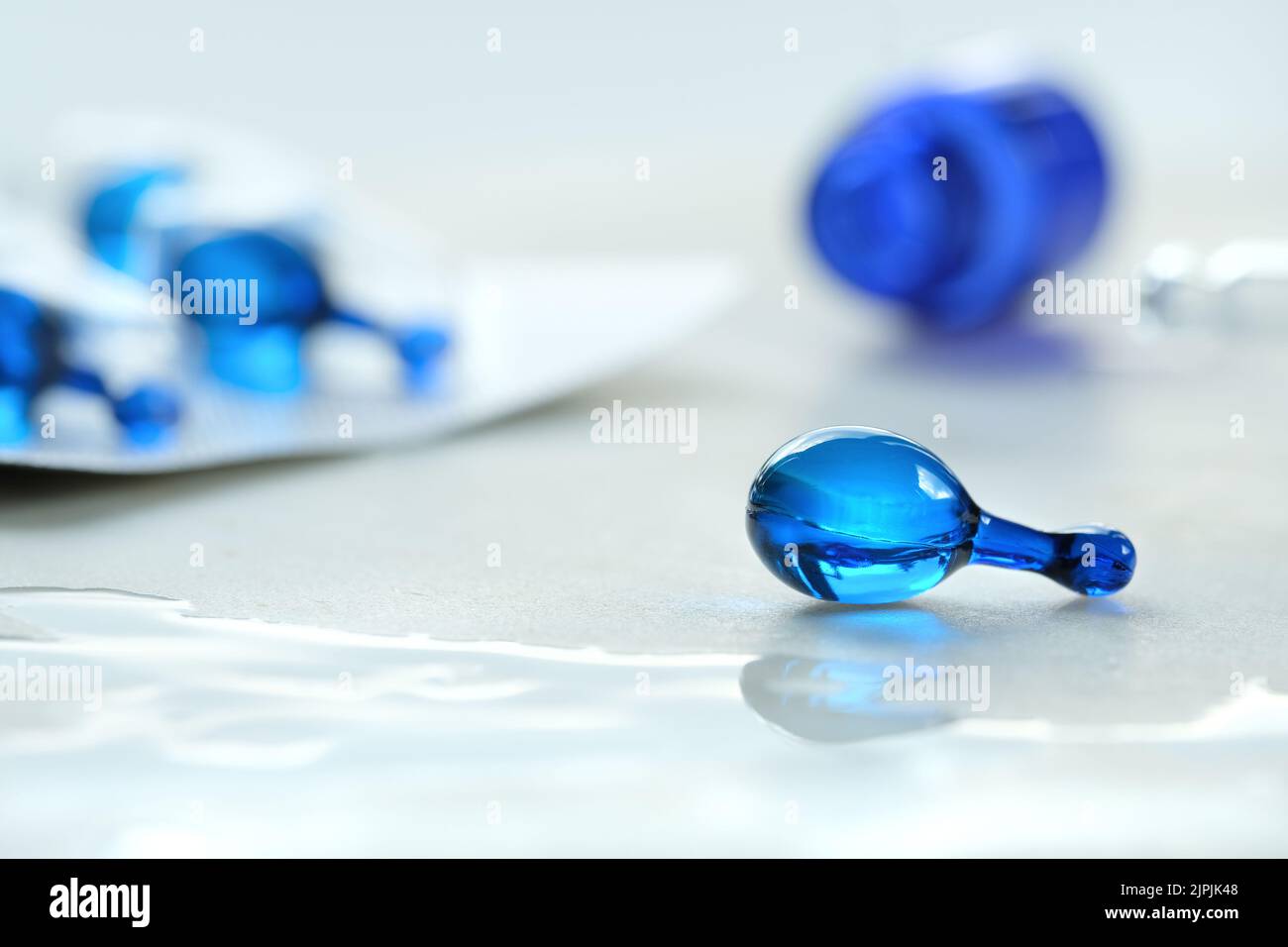 Blue serum capsules for healthy skin, close-up on off white background ...