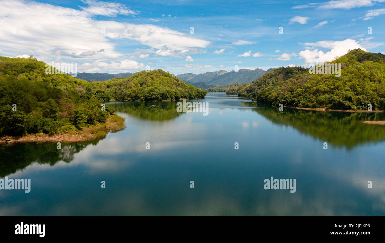 A river among mountains and hills with a reflecting blue sky and clouds ...