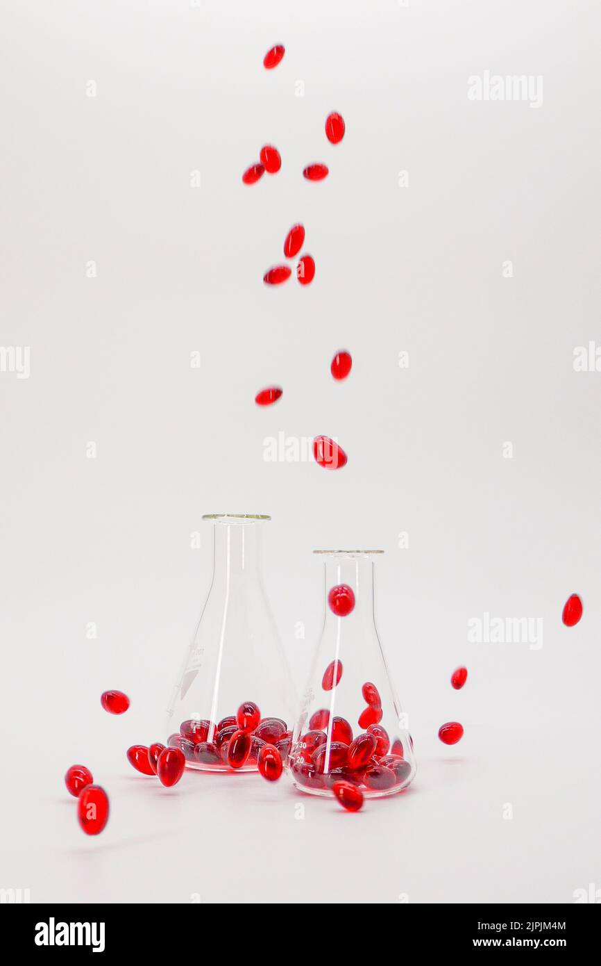 Krill oil red gelatin capsules in laboratory flasks on a white ...