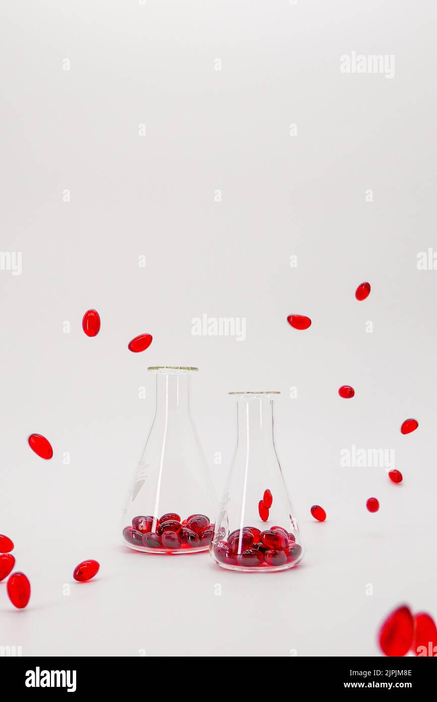 Krill oil capsules in laboratory transparent flasks on a white ...