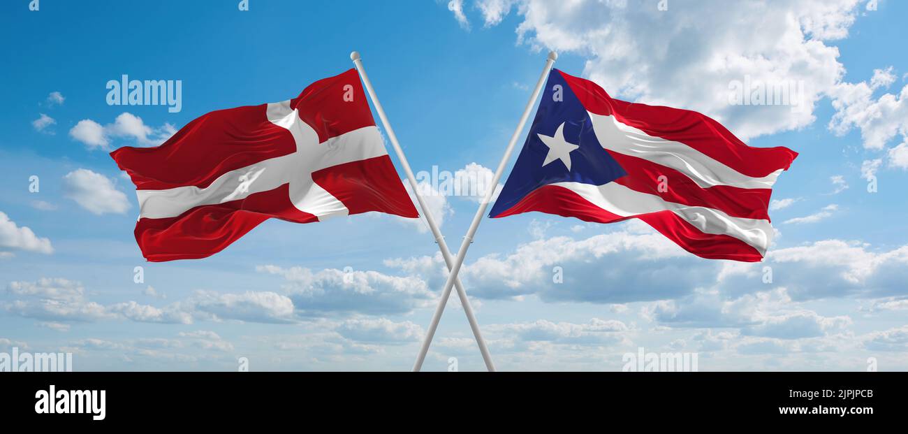 two crossed flags Puerto Rico and Denmark waving in wind at cloudy sky. Concept of relationship ...