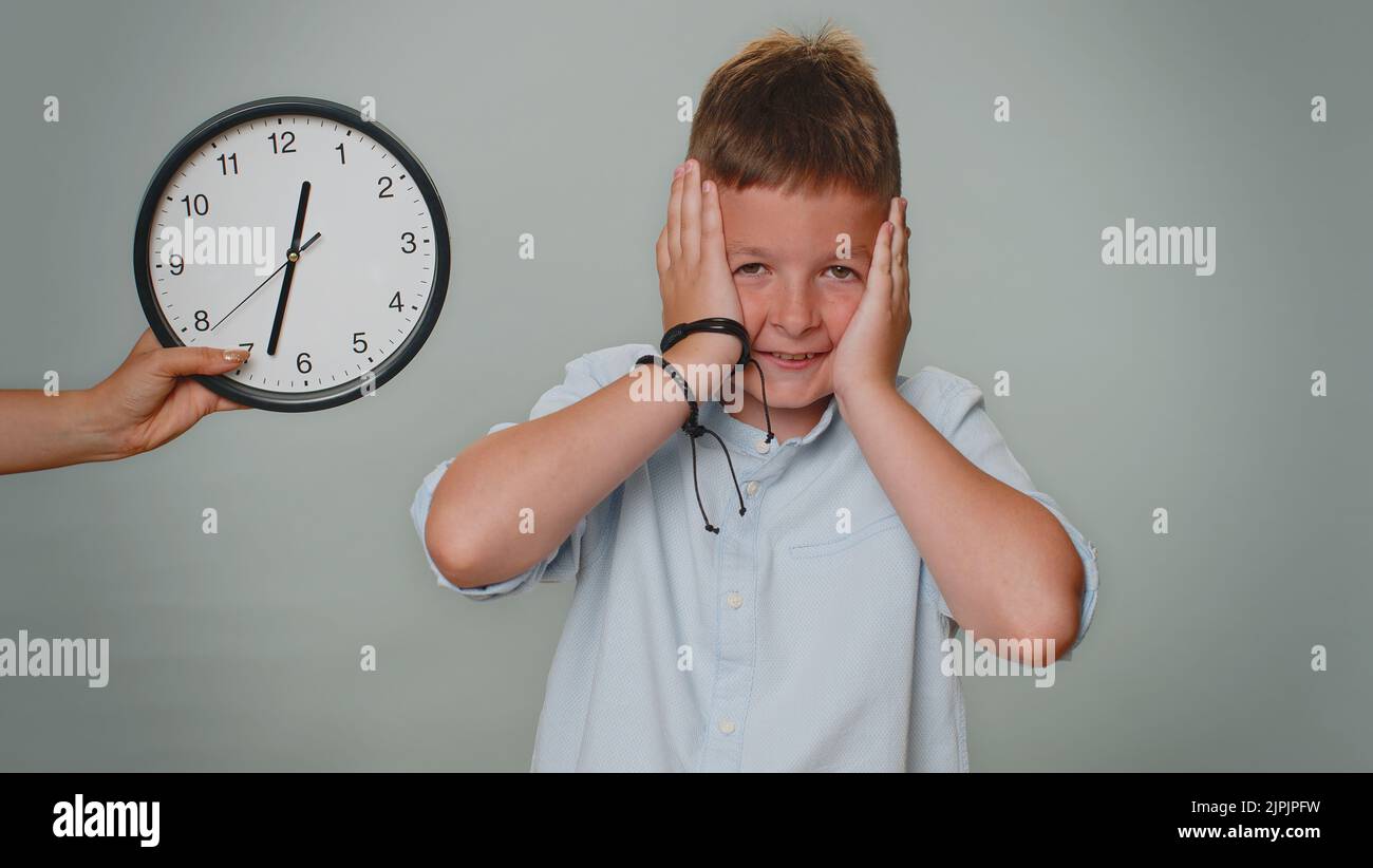 Portrait of toddler kid boy with anxiety checking time on clock ...