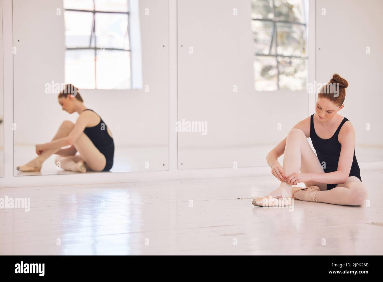 Female ballet dancer preparing pointe shoes in a ballet hub, studio or ...