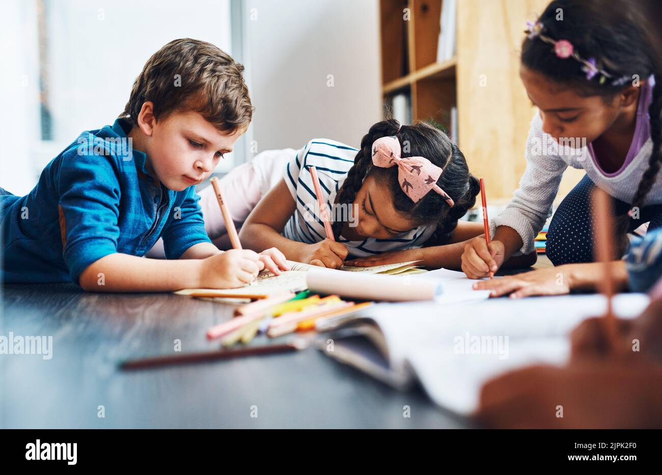 Keeping their creative minds busy. kids coloring in while lying on the ...
