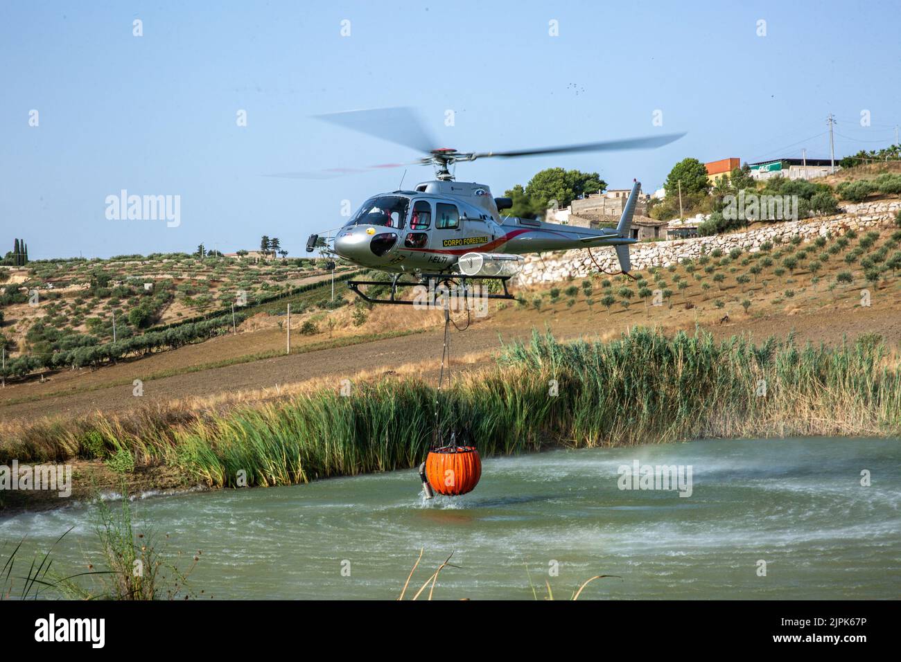 The forest ranger's helicopter fetching water from an artificial lake to put out the fire. On a ...