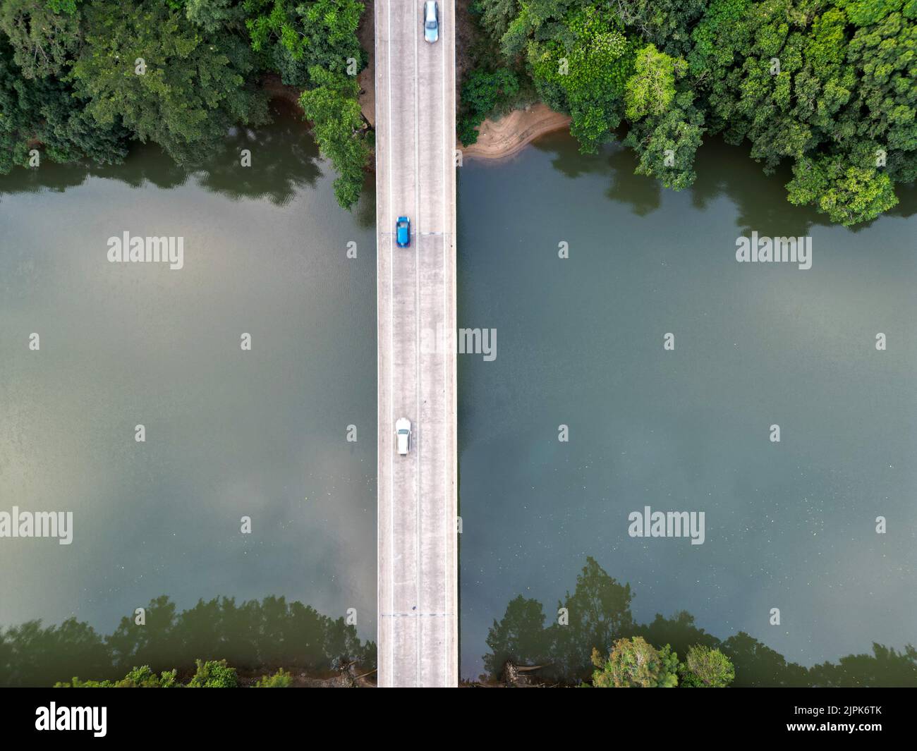 Downward aerial view of tropical river bridge with cars passing over ...