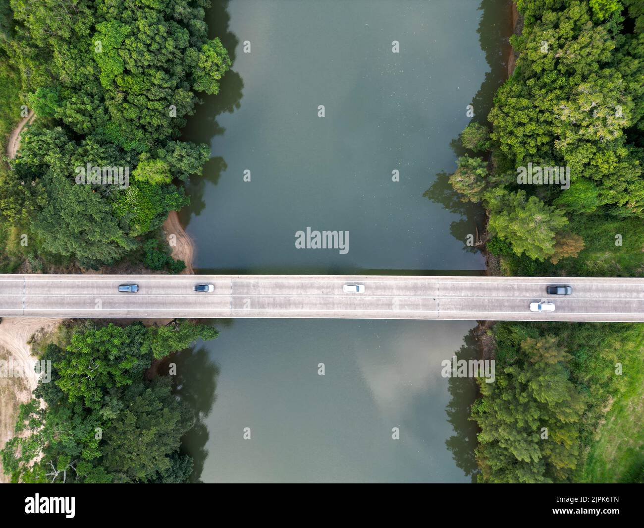 Downward aerial view of tropical river bridge with cars passing over ...