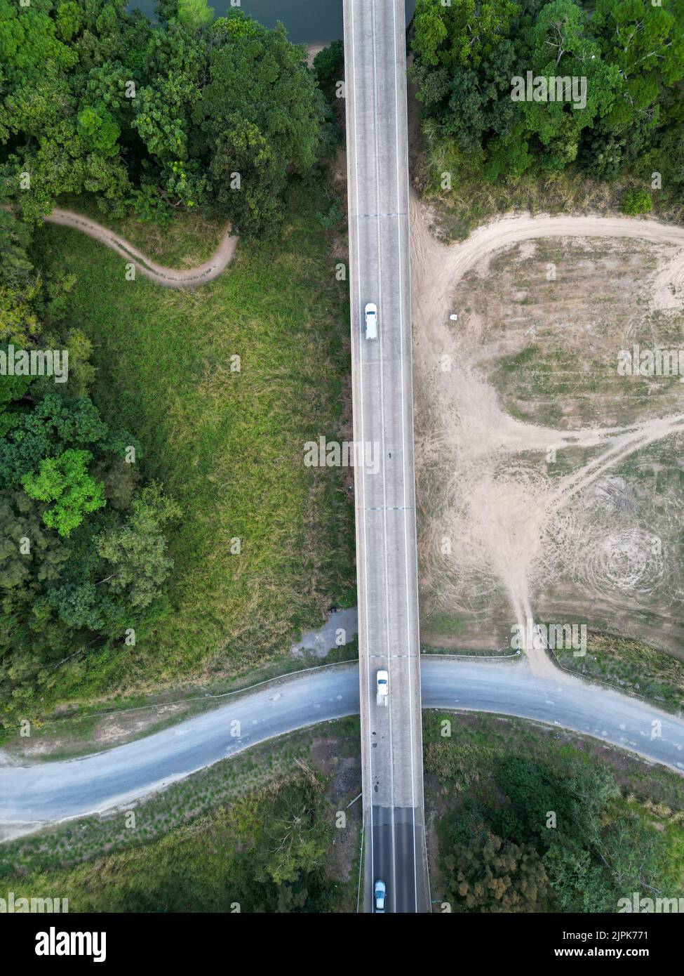 Downward aerial view of tropical river bridge with cars passing over ...