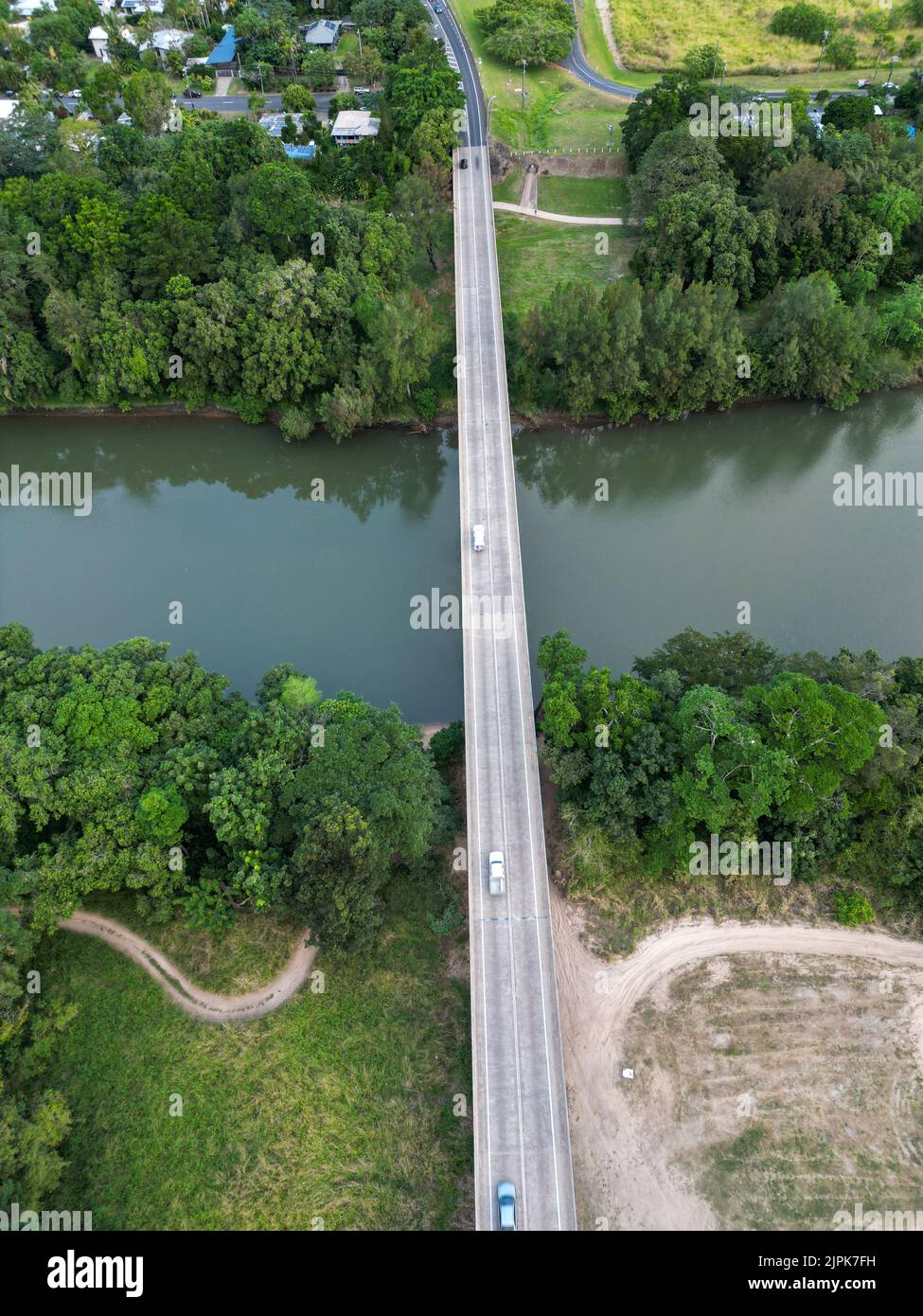 Downward aerial view of tropical river bridge with cars passing over ...