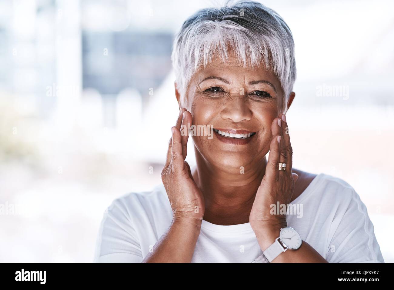 Glowing everyday. Portrait of a cheerful mature woman holding her face ...