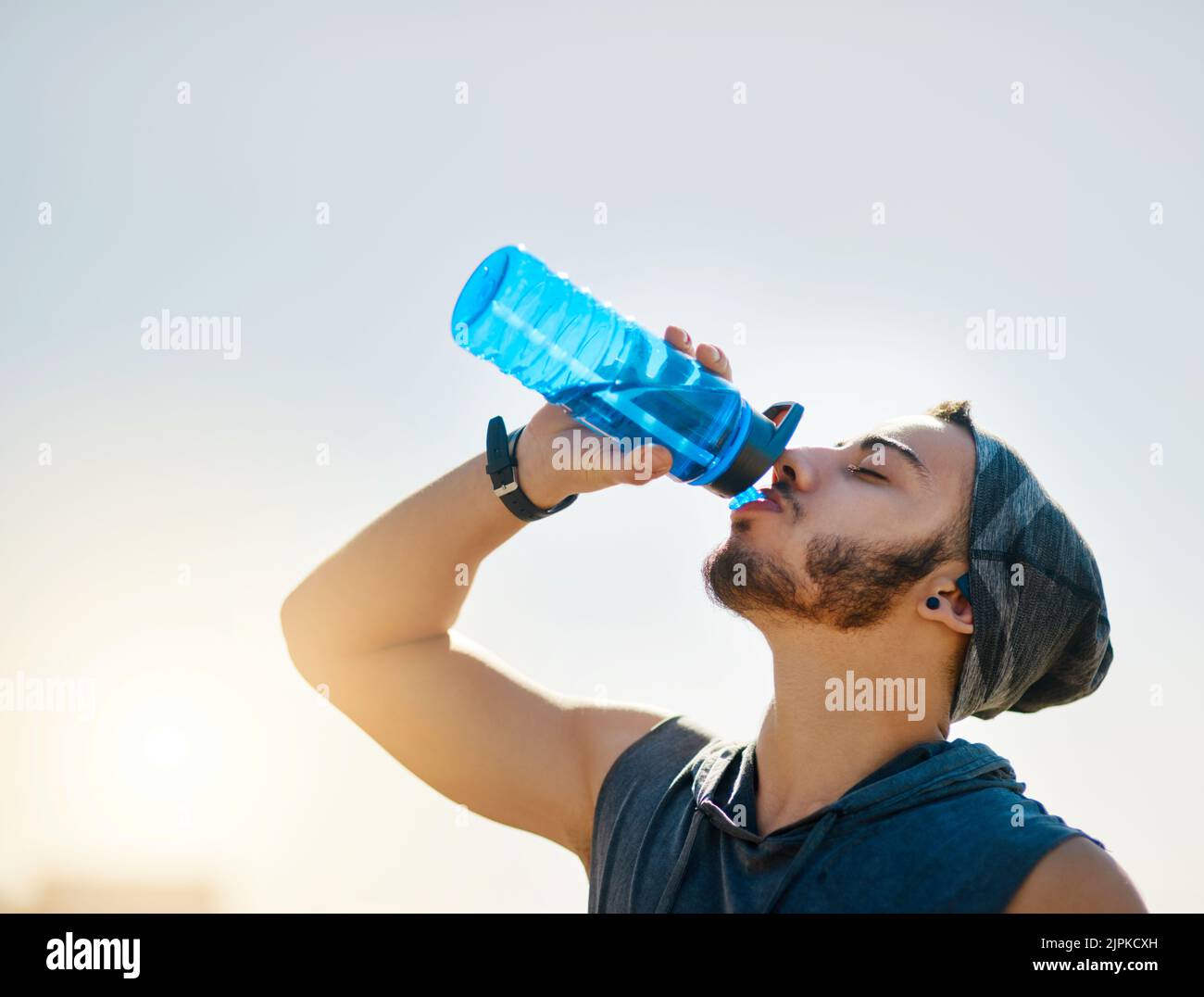 It fuels a better workout. a sporty young man drinking water while ...