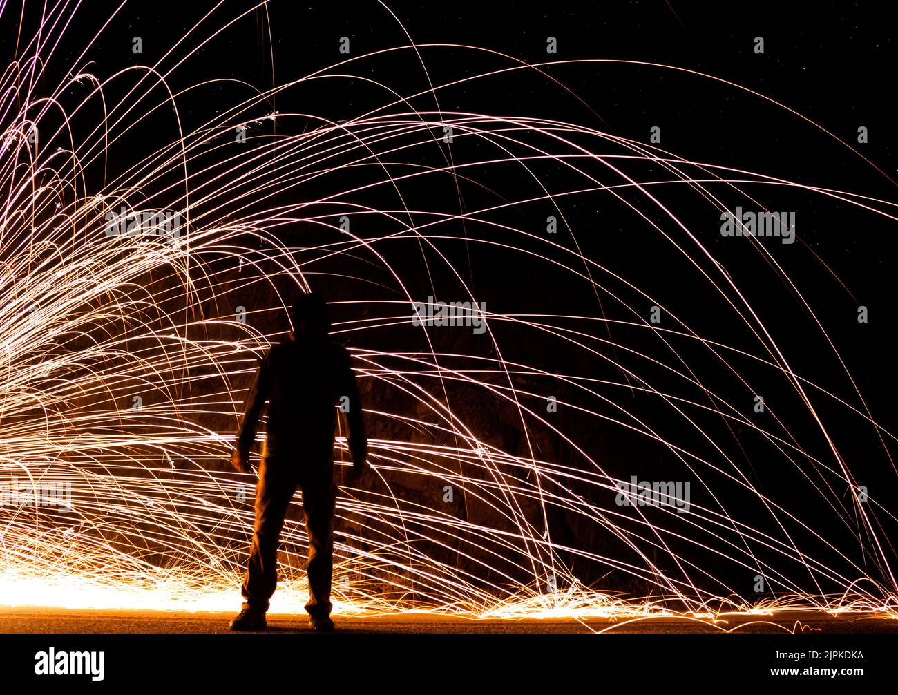 Silhouette of a man in front of glowing steel sparks. Light painting ...