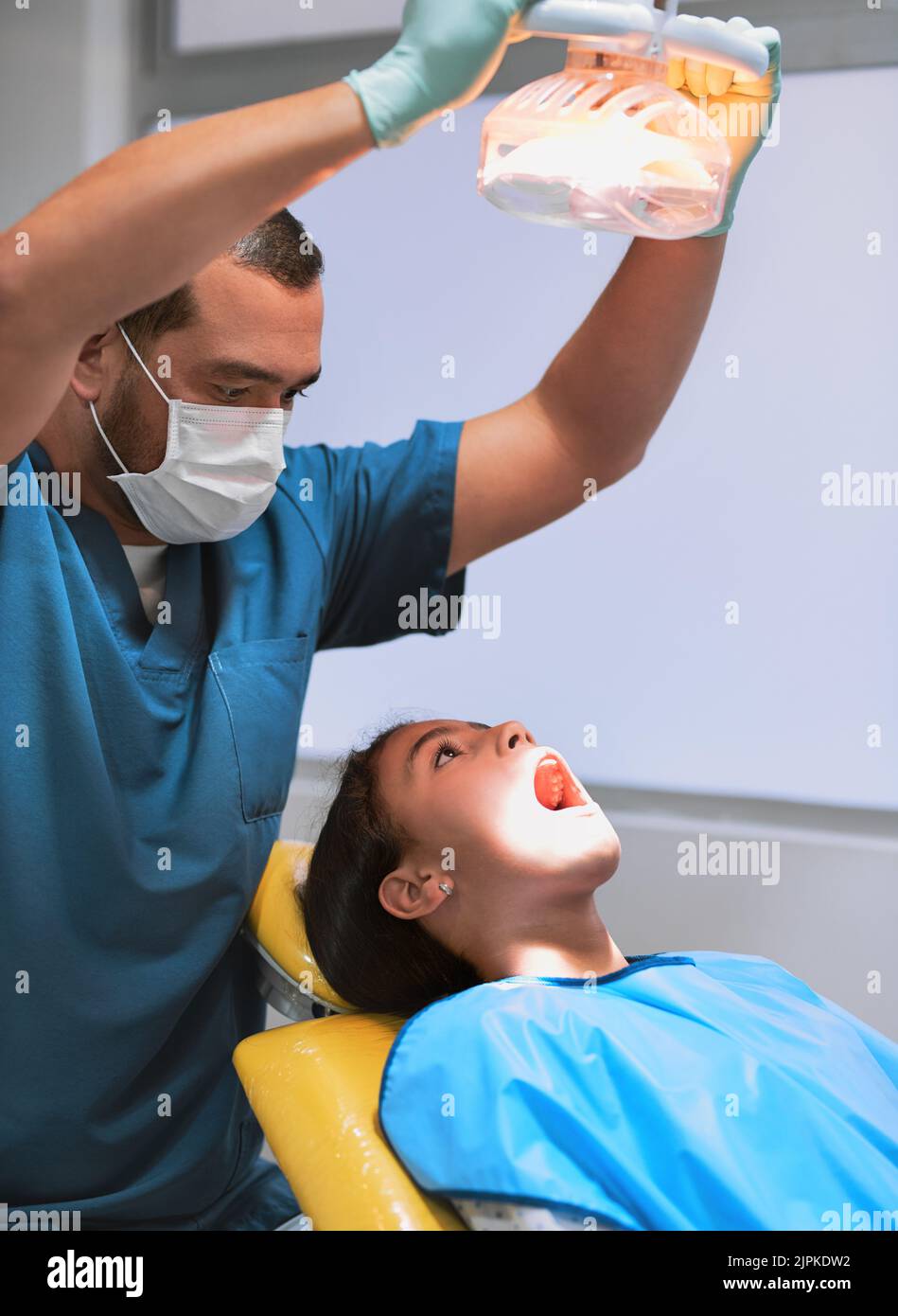 Shining brightly. a young little girl lying down on a dentist chair ...