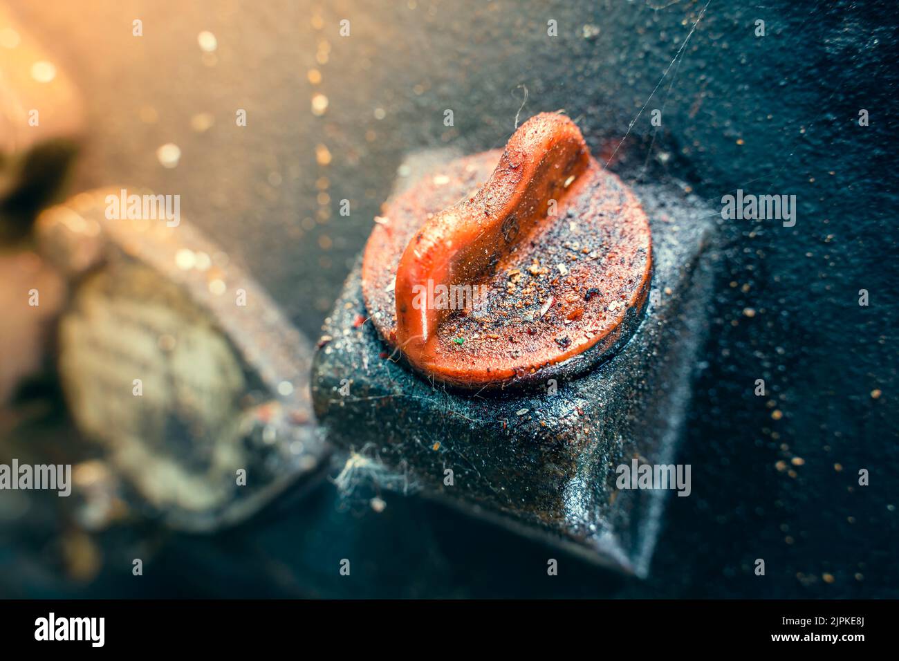 Close-up red plastic oil dipstick cap in the body of a dirty motoblock ...